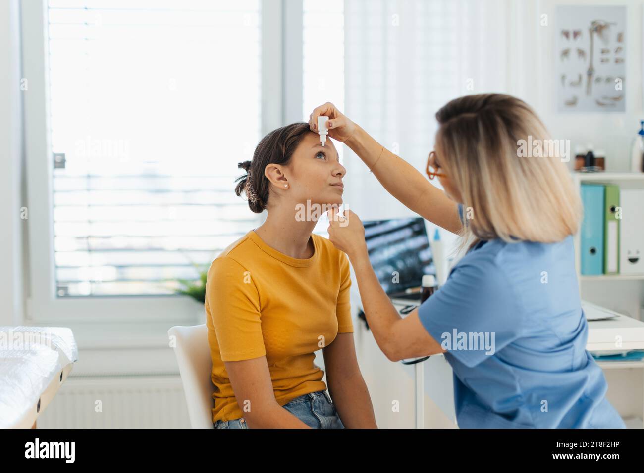 Pediatrician putting eye drops into girls eyes. The ophthalmologist ...