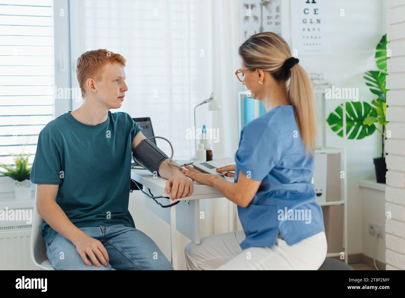Doctor measuring boy's blood pressure, using blood pressure monitor ...