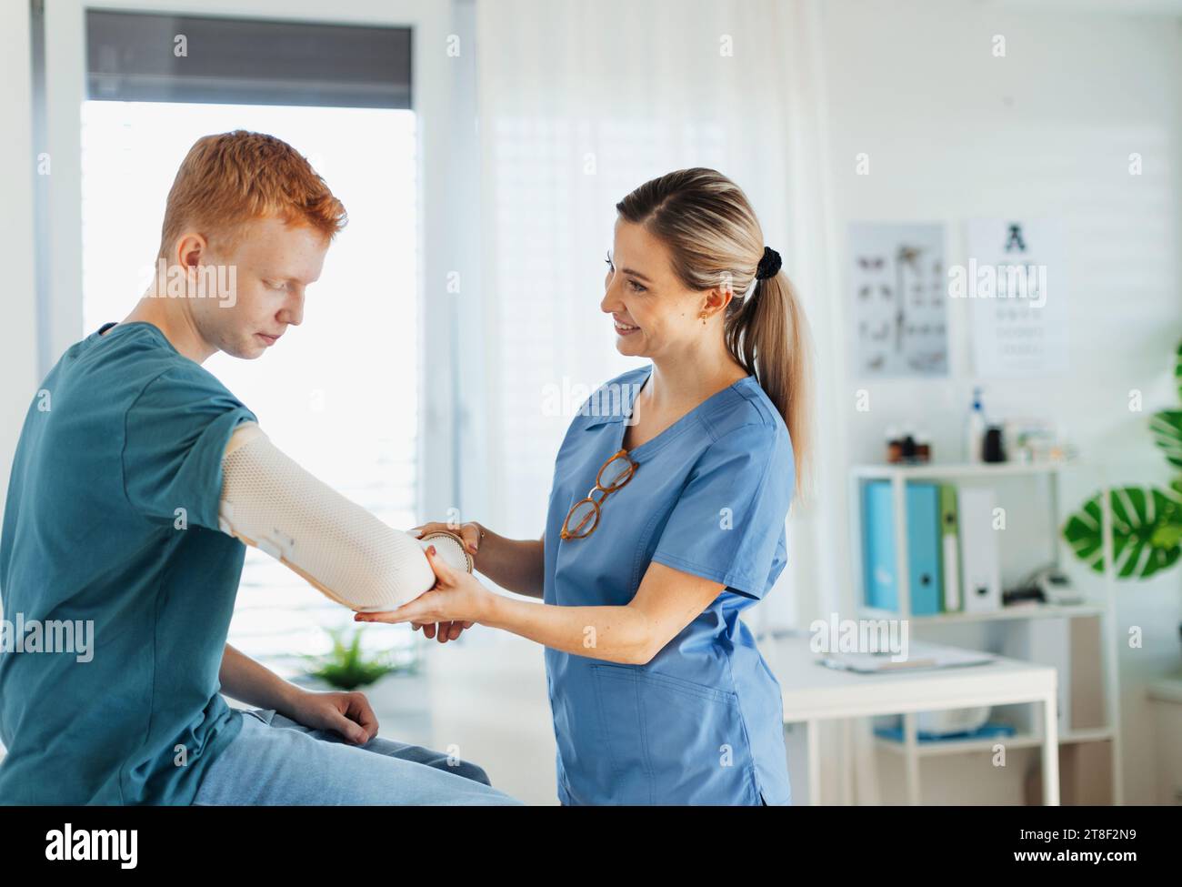 Doctor checking the orthopedic cast, brace on a teenage patient's ...