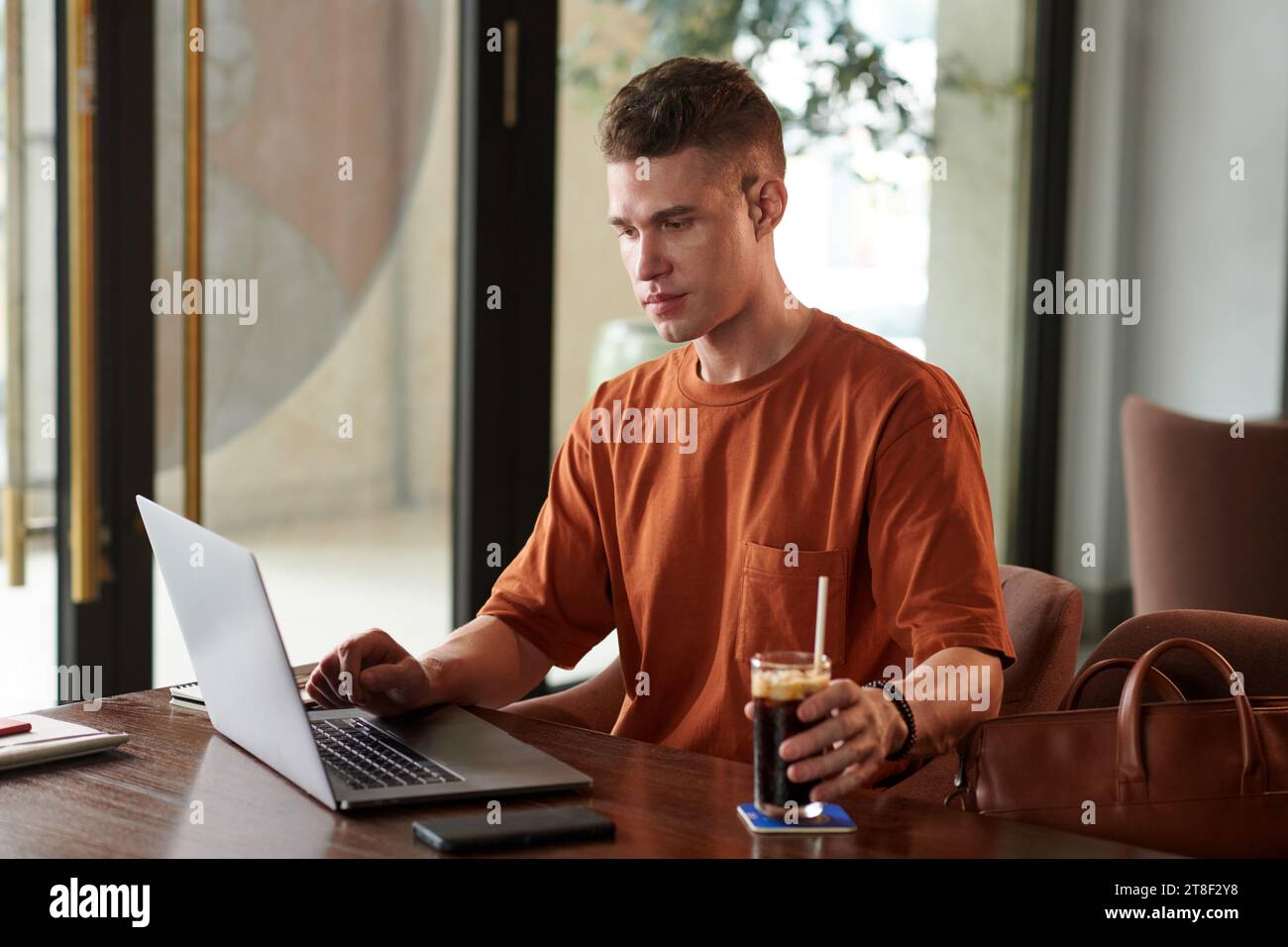 Young software developer drinking iced soft drink when working on ...
