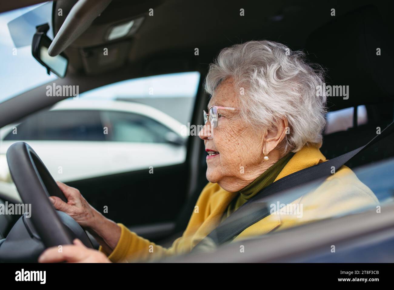 Happy senior woman driving car alone, enjoying car ride. Safe driving ...