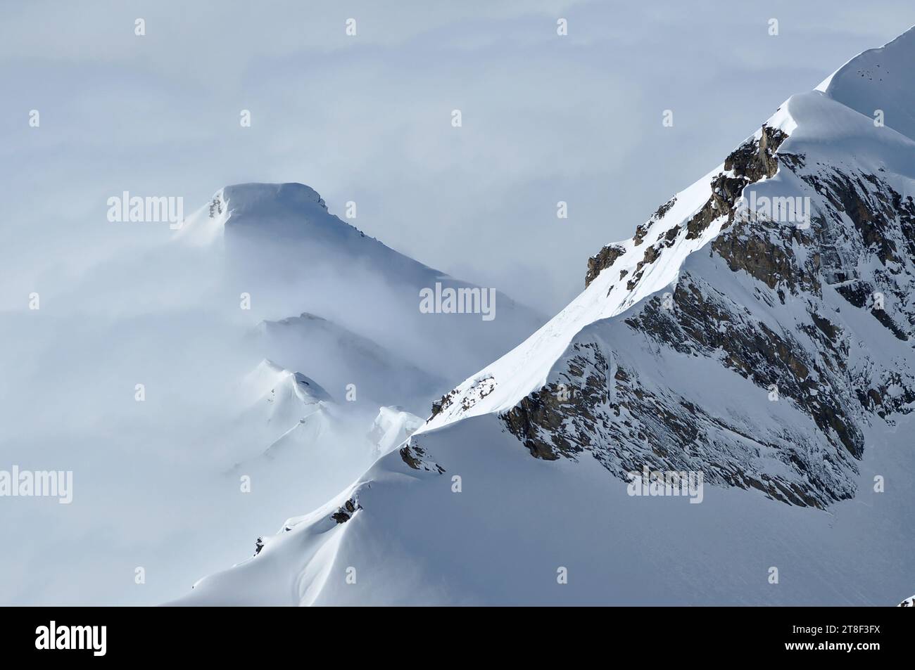 Snow covered high mountains, fog and clouds raising from above. Alps ...