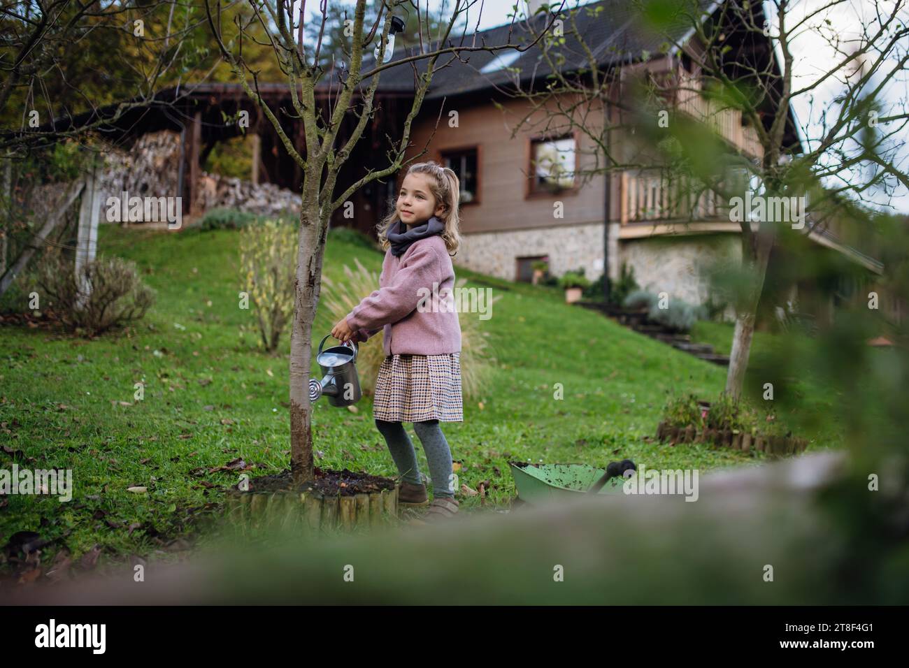 Little girl watering tree in garden, using collected rainwater. Concept ...