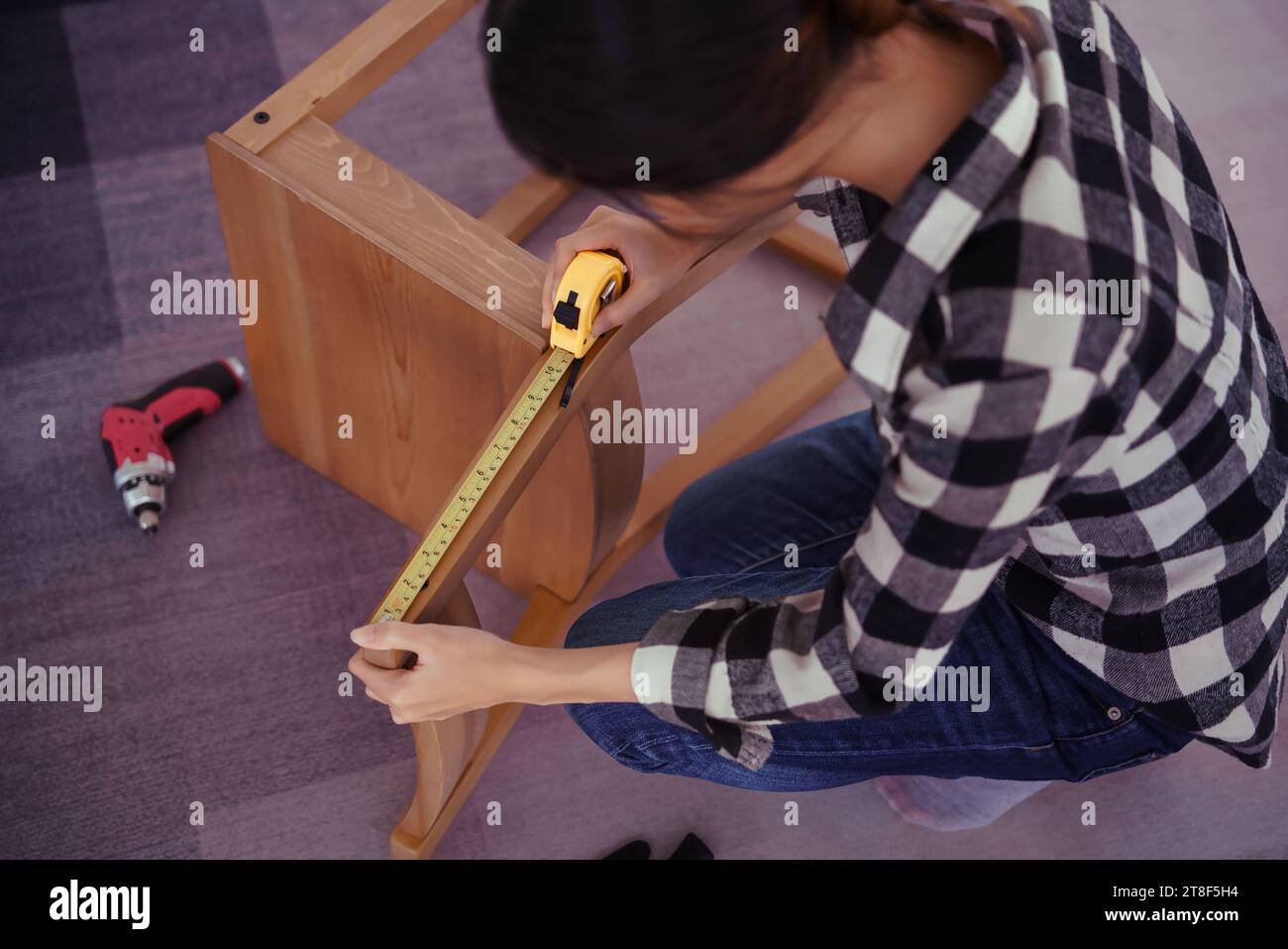 Women measuring length of chair with measure tape while assembling and ...