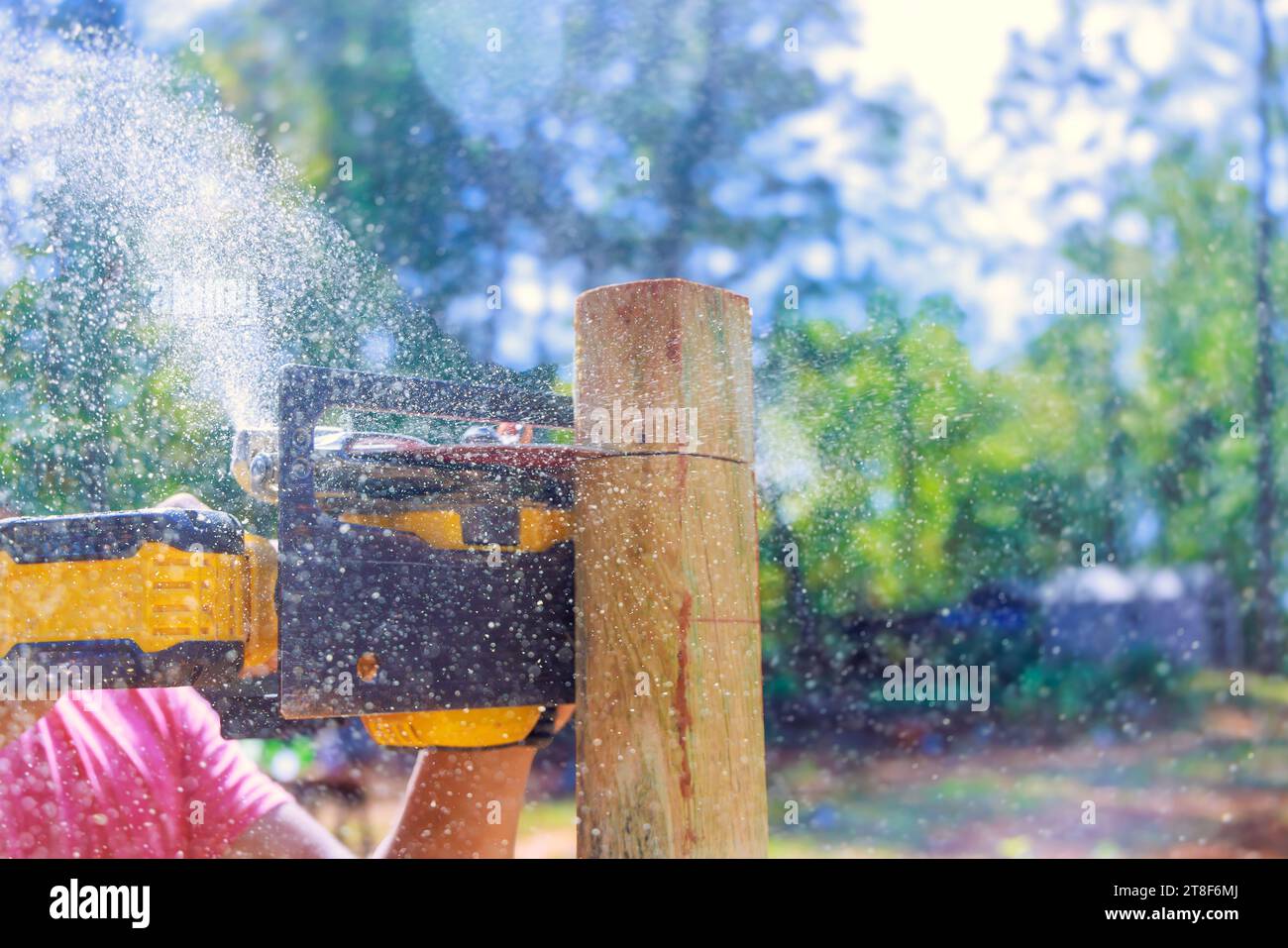 Cutting wooden post for fence with an electric saw Stock Photo - Alamy