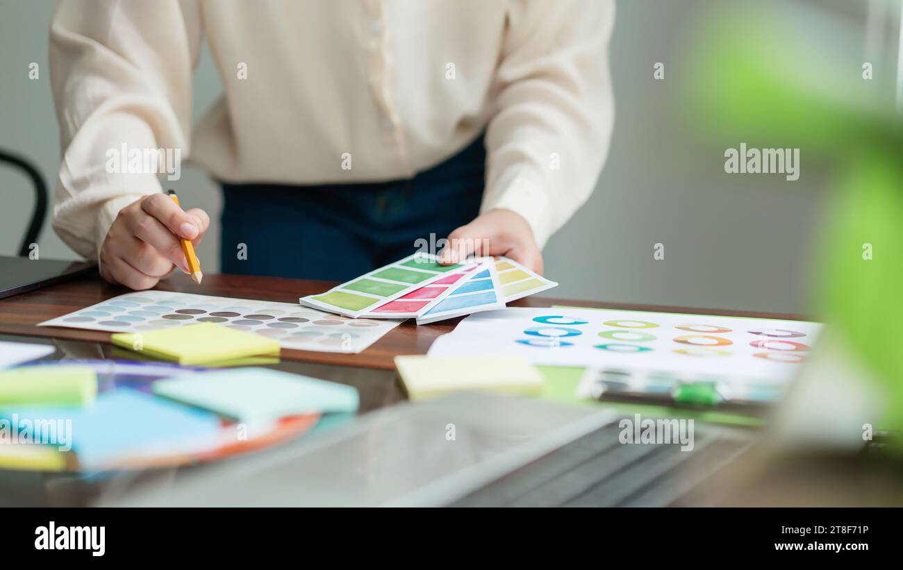 Creative graphic designer holding color sample and comparing color ...