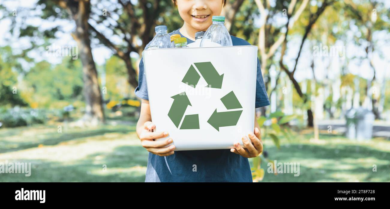 Cheerful young asian boy holding recycle symbol bin on daylight natural ...