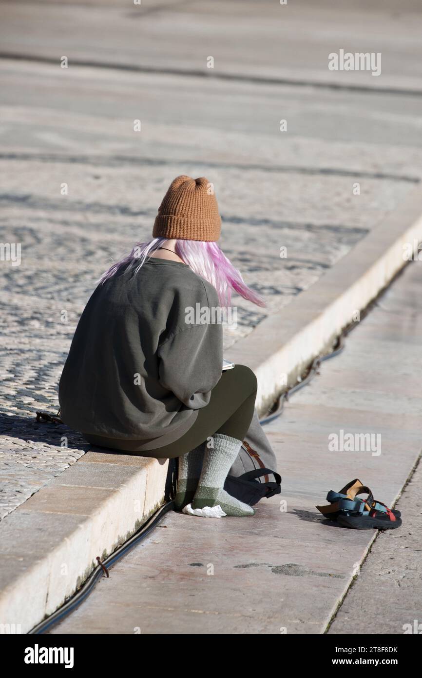Homeless woman sitting on the sidewalk looking at her shoes, the ...