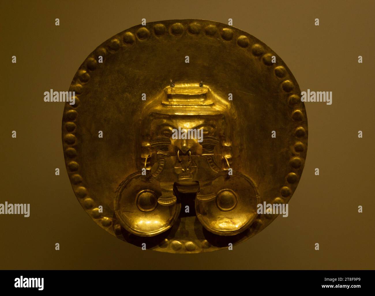 Closeup to an ancient indigenous rounded golden pectoral with a face at ...