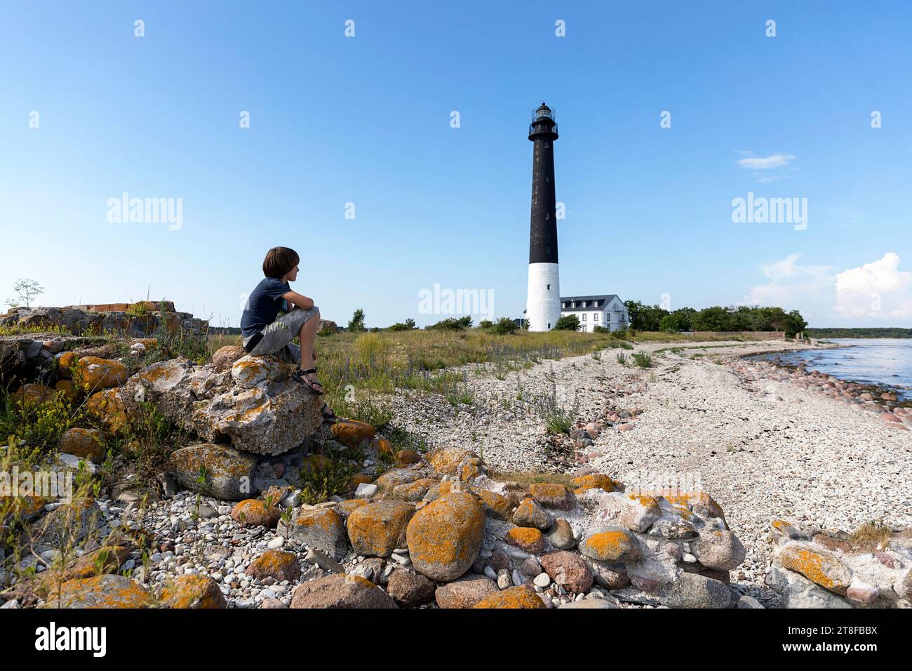 Tourist sitting near Sorve lighthouse on a Sõrve poolsaar, a peninsula ...