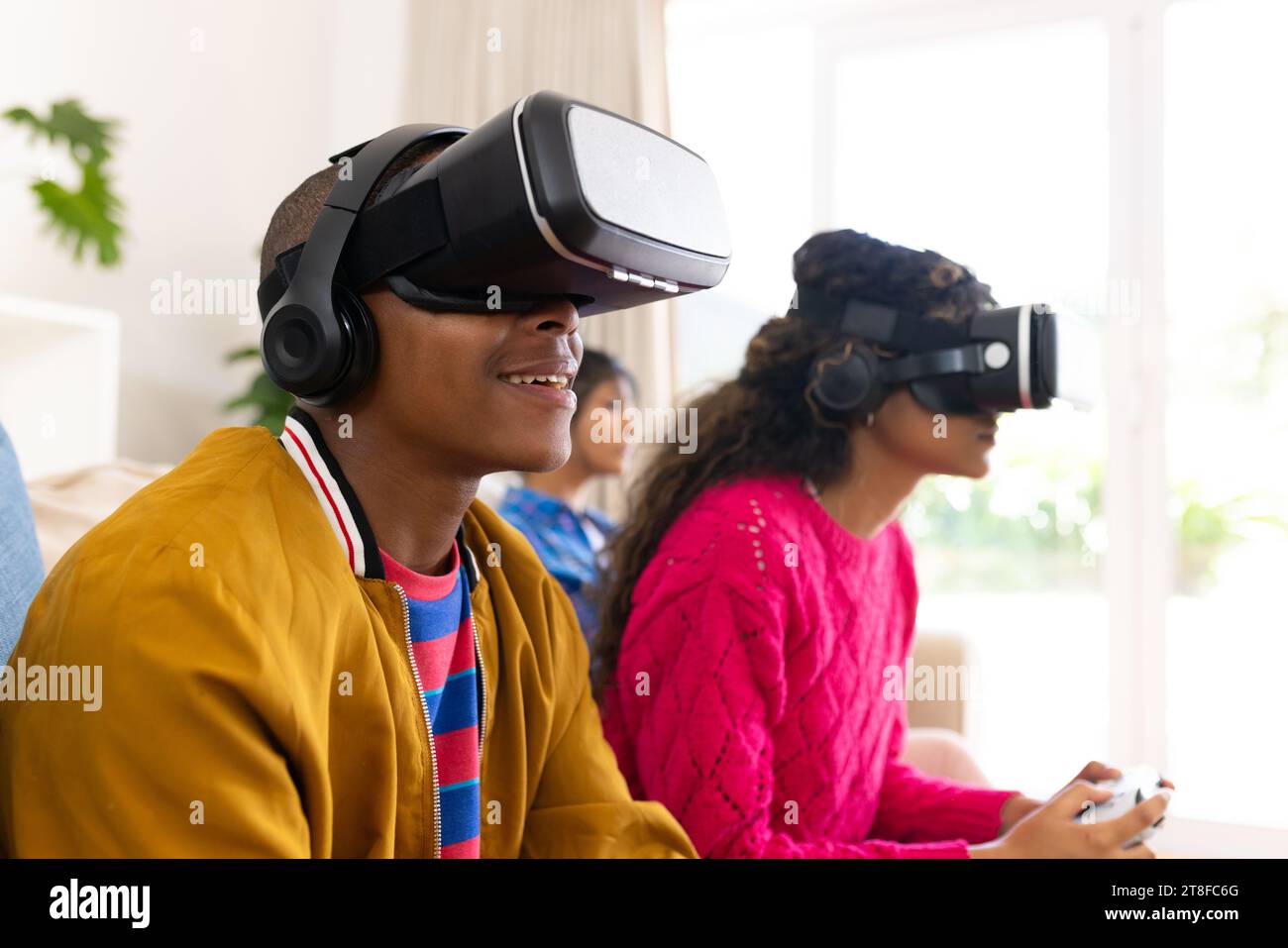 Happy diverse group of teenage friends using vr headsets and playing ...