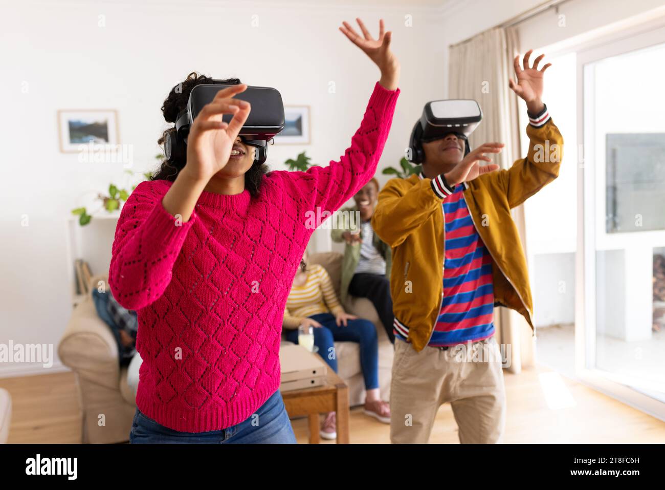 Happy diverse group of teenage friends using vr headsets and playing at ...