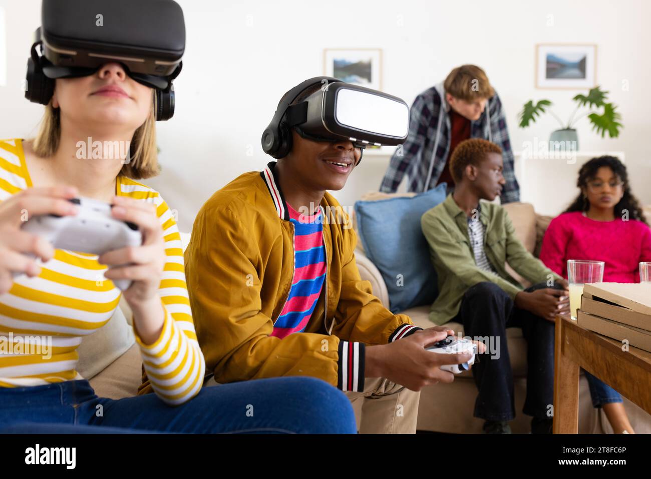 Happy diverse group of teenage friends using vr headsets and playing ...