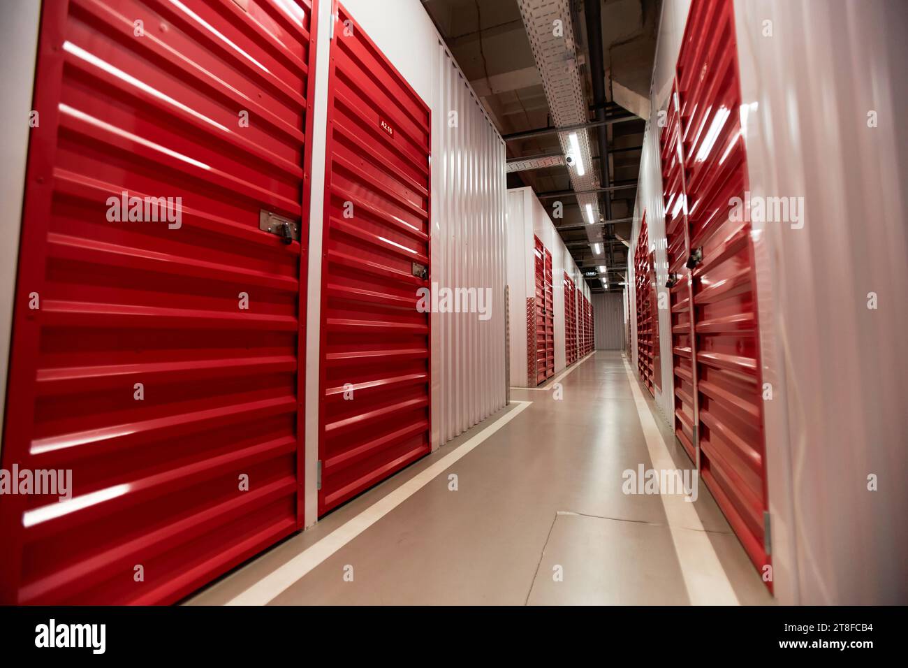 Empty corridor in self-storage with locked red doors Stock Photo - Alamy