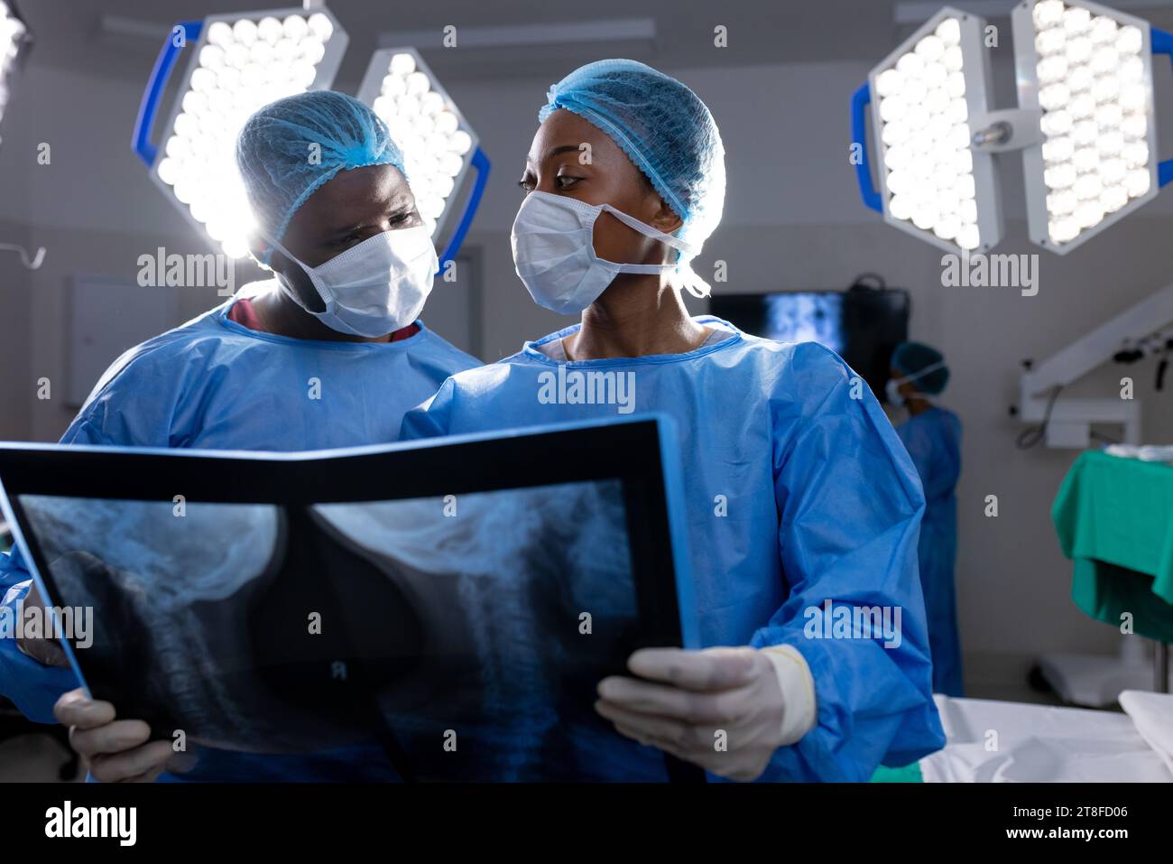 African american male and female doctors with face masks looking at x ...