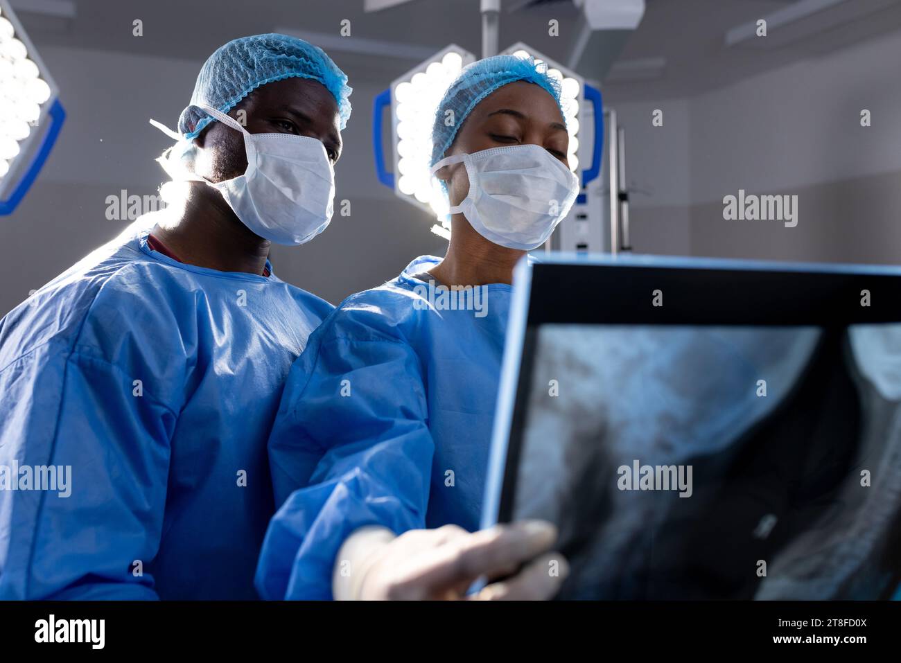 African american male and female doctors with face masks looking at x ...