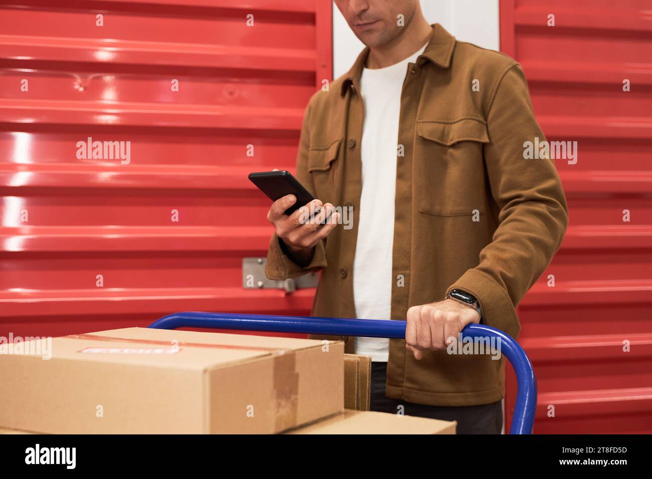 Customer standing next to cart with boxes and checking message with ...
