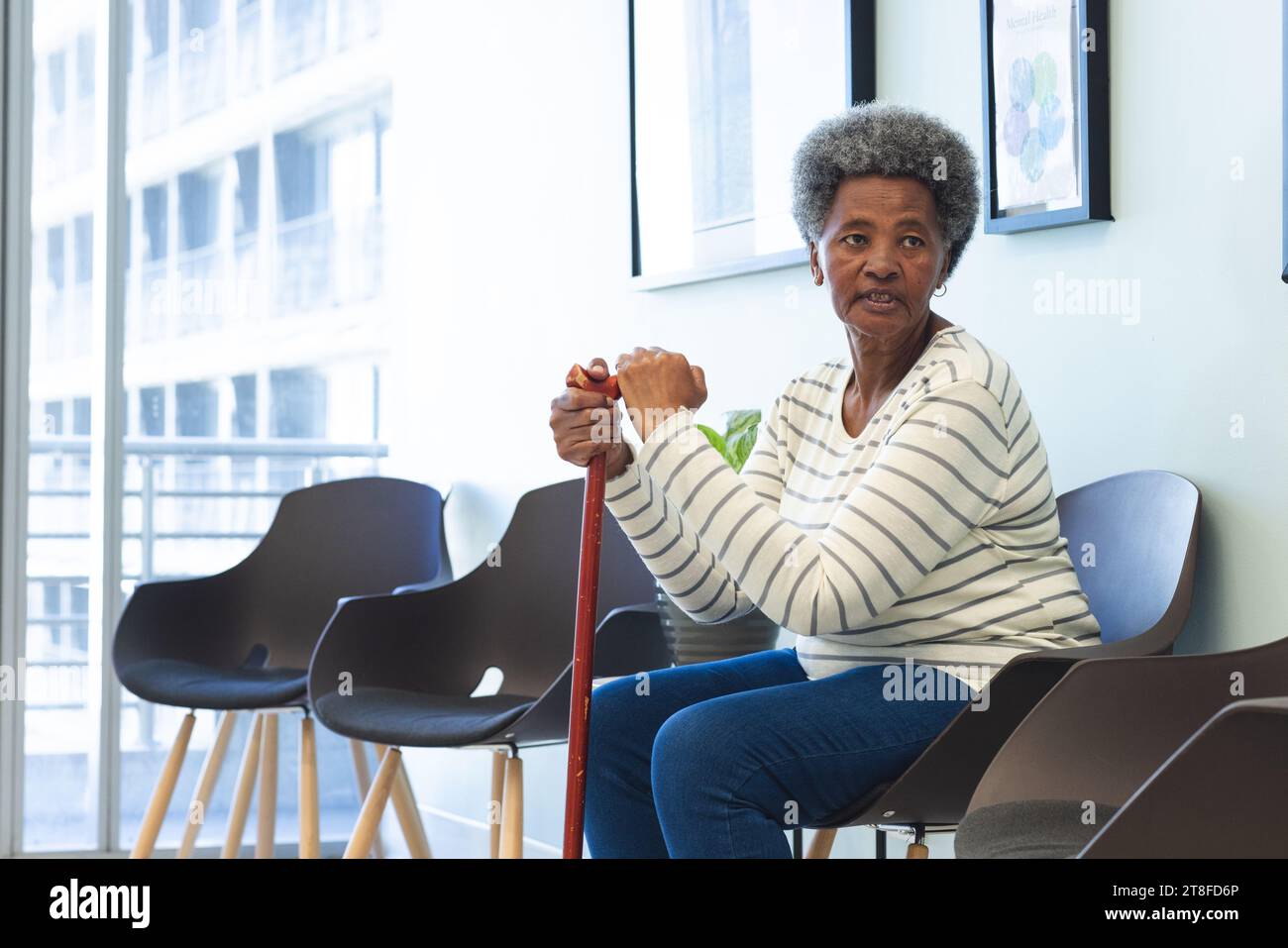 African american senior woman with walking stick sitting in hospital ...