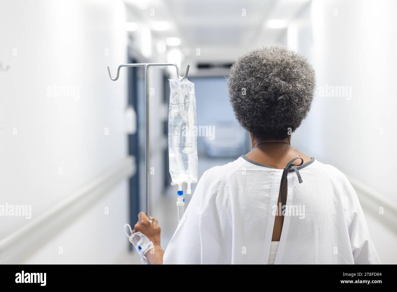 Back of african american senior female patient with drip walking in ...