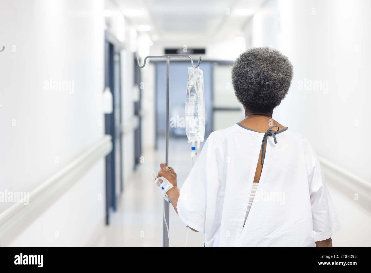 Back of african american senior female patient with drip walking in ...
