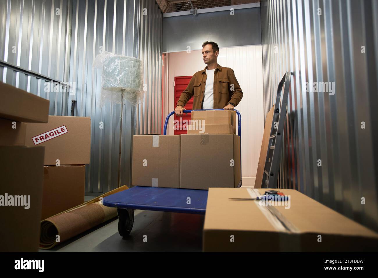 Pensive man pushing cart with belongings inside storage unit Stock ...