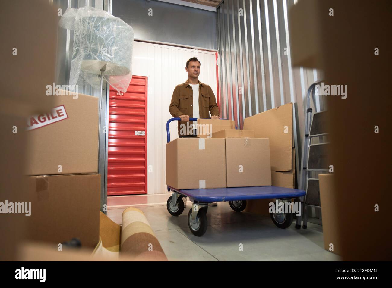 Customer pushing cart with belongings inside big unit he rented in self ...