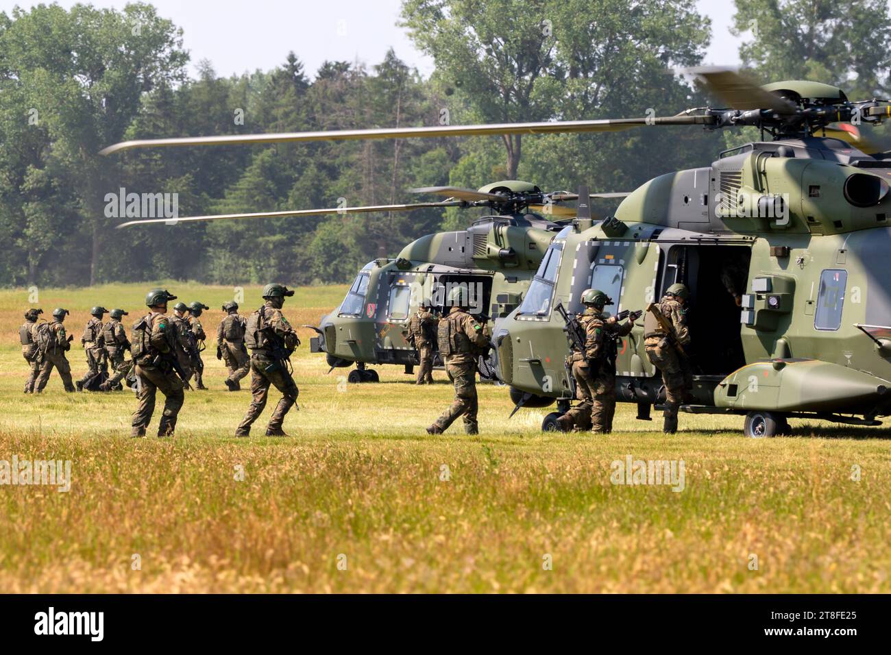 German army soldiers entering two NH90 helicopters at a landing zone ...