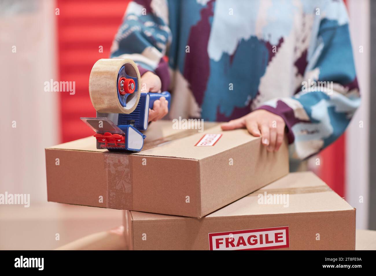 Hands of woman taping boxes with belongings when packing fragile items ...