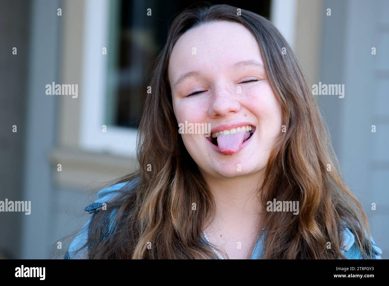 Sassy kid shows her silly side by posing with a tongue out and funny ...