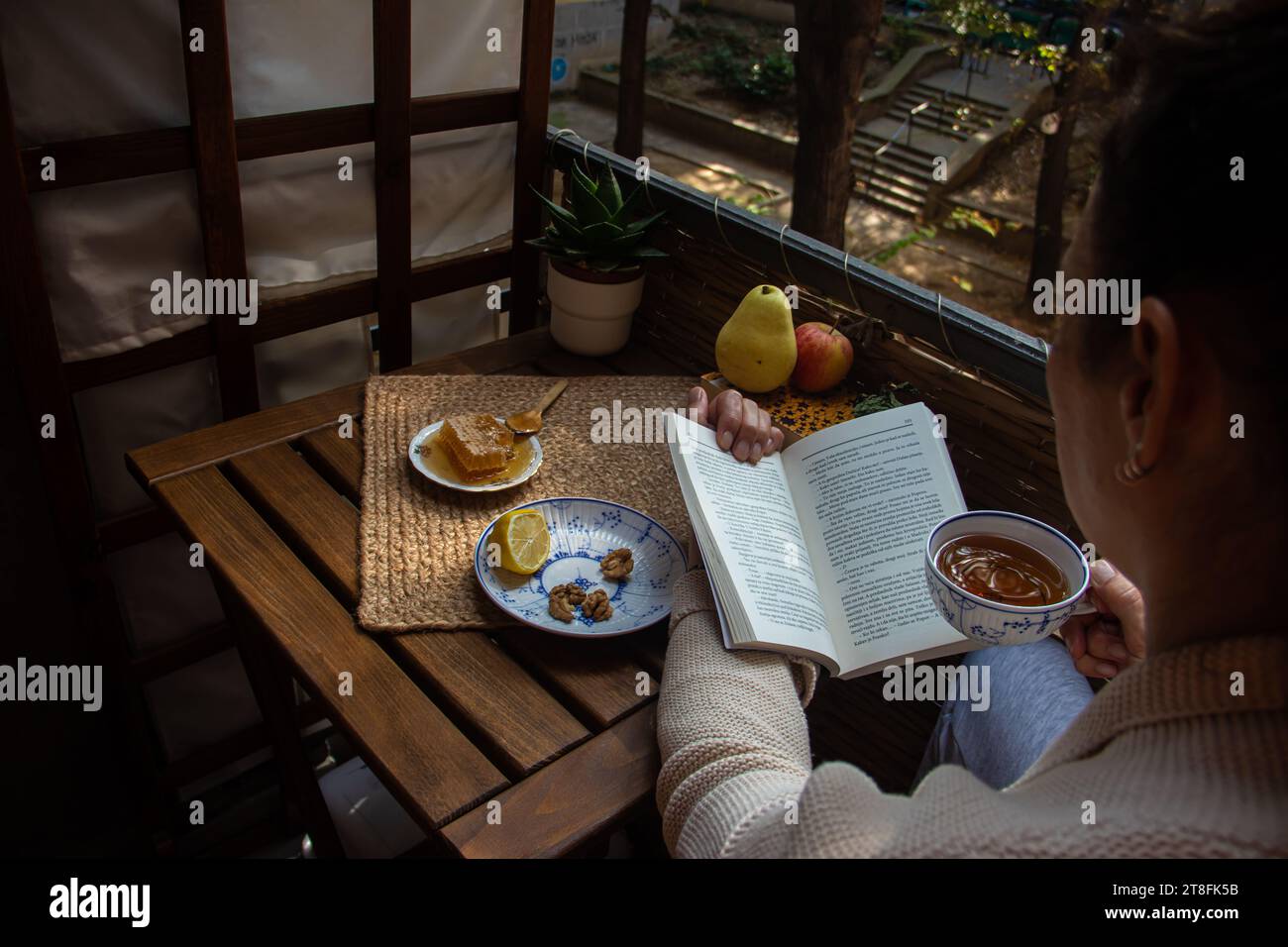 Picture from back of young woman enjoying quiet morning time at balcony ...