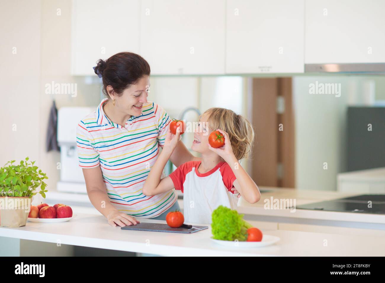 Family cooking dinner. Mom and child cook spaghetti in white sunny ...