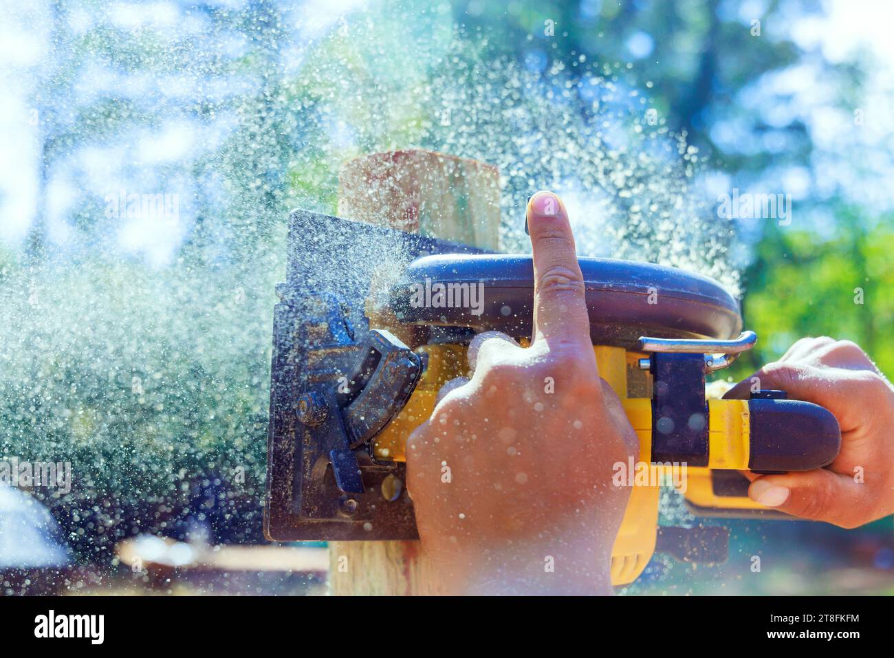 Using an electric saw to cut wooden post for fence Stock Photo - Alamy