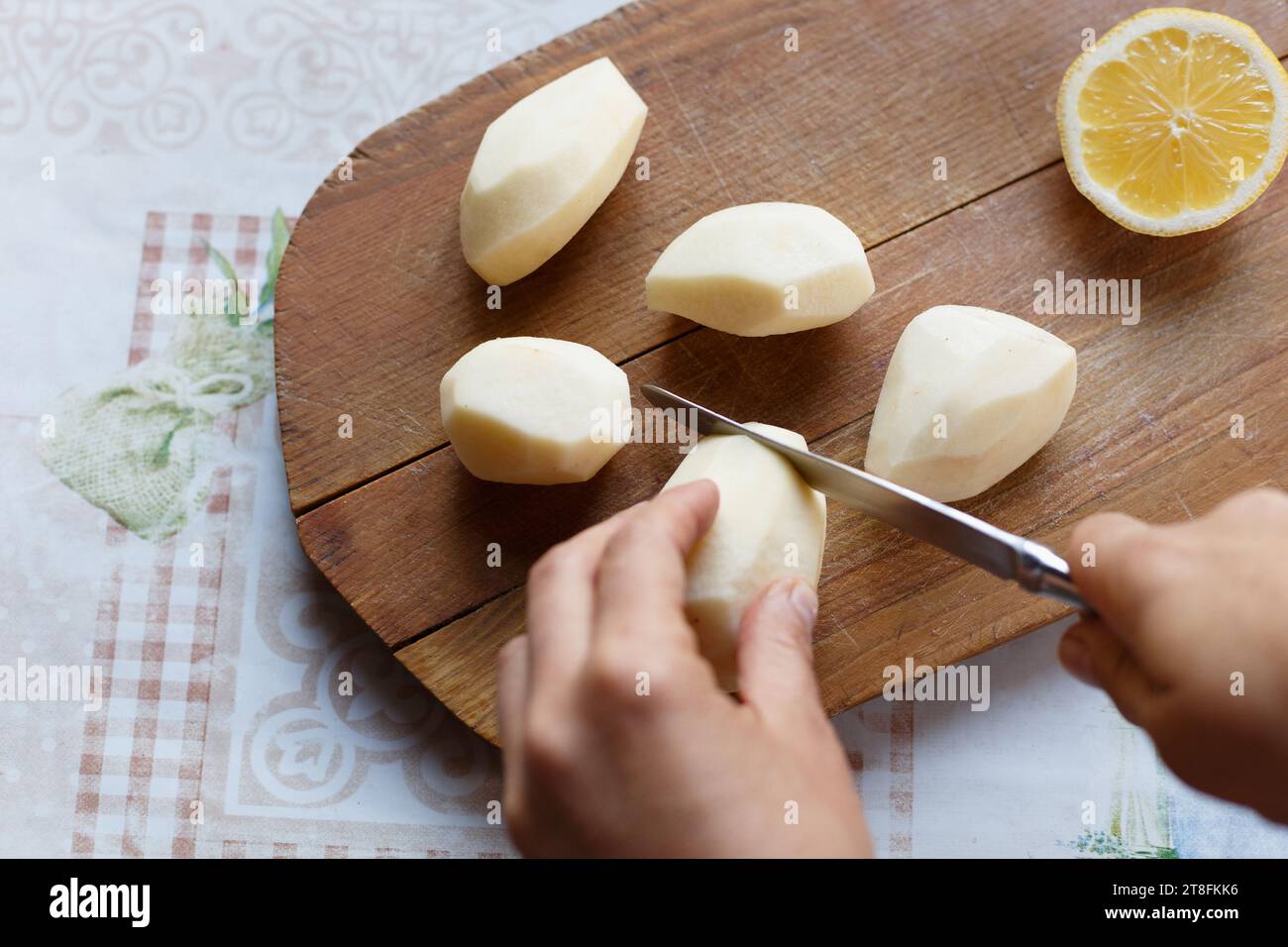 Cutting peeled potatoes on the cutting board, close Stock Photo - Alamy