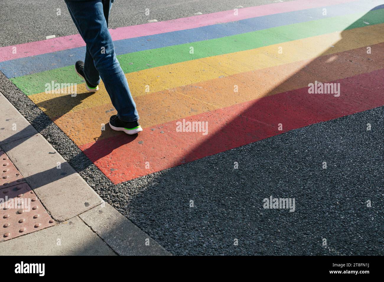 A person walking over a vibrant rainbow crossing on a sunny day in ...