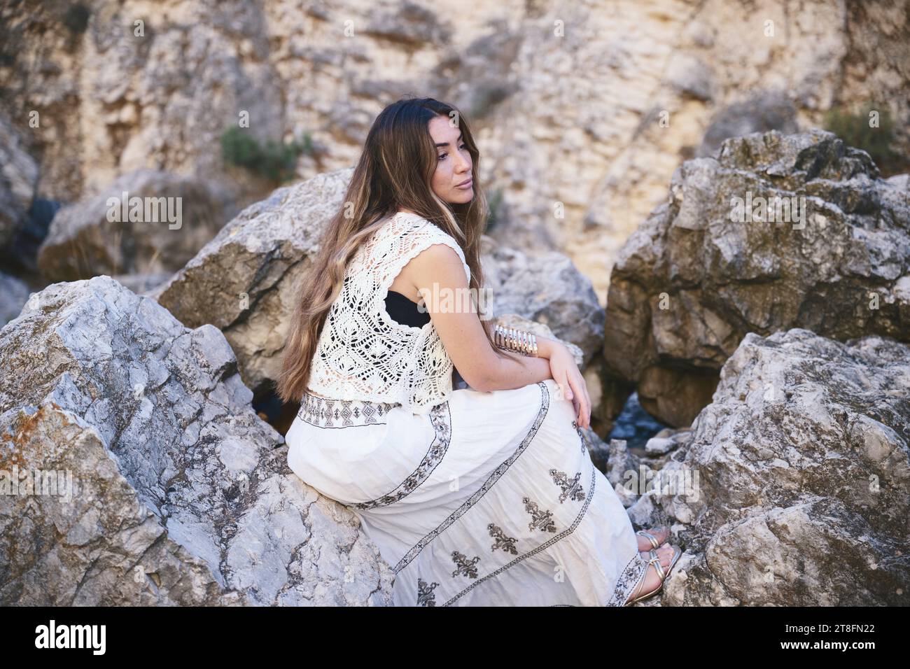 Side view of woman in a sleeveless white dress adorned with patterns ...
