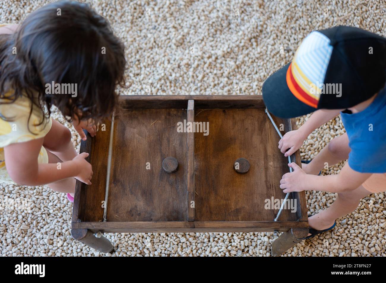 Overhead view of two young kids collaboratively fixing a wooden drawer ...