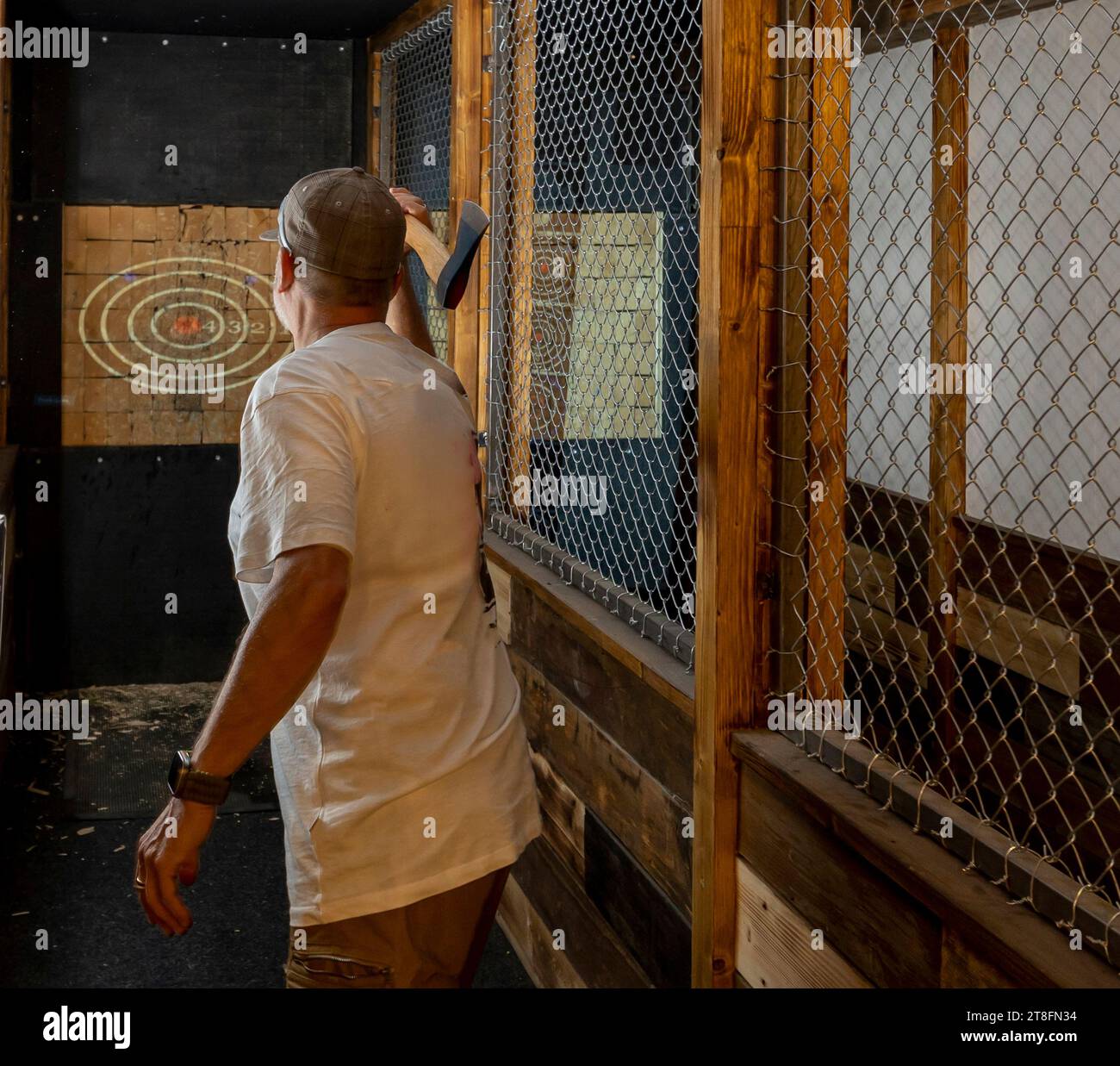 A focused man participates in the sport of axe throwing, aiming at a ...