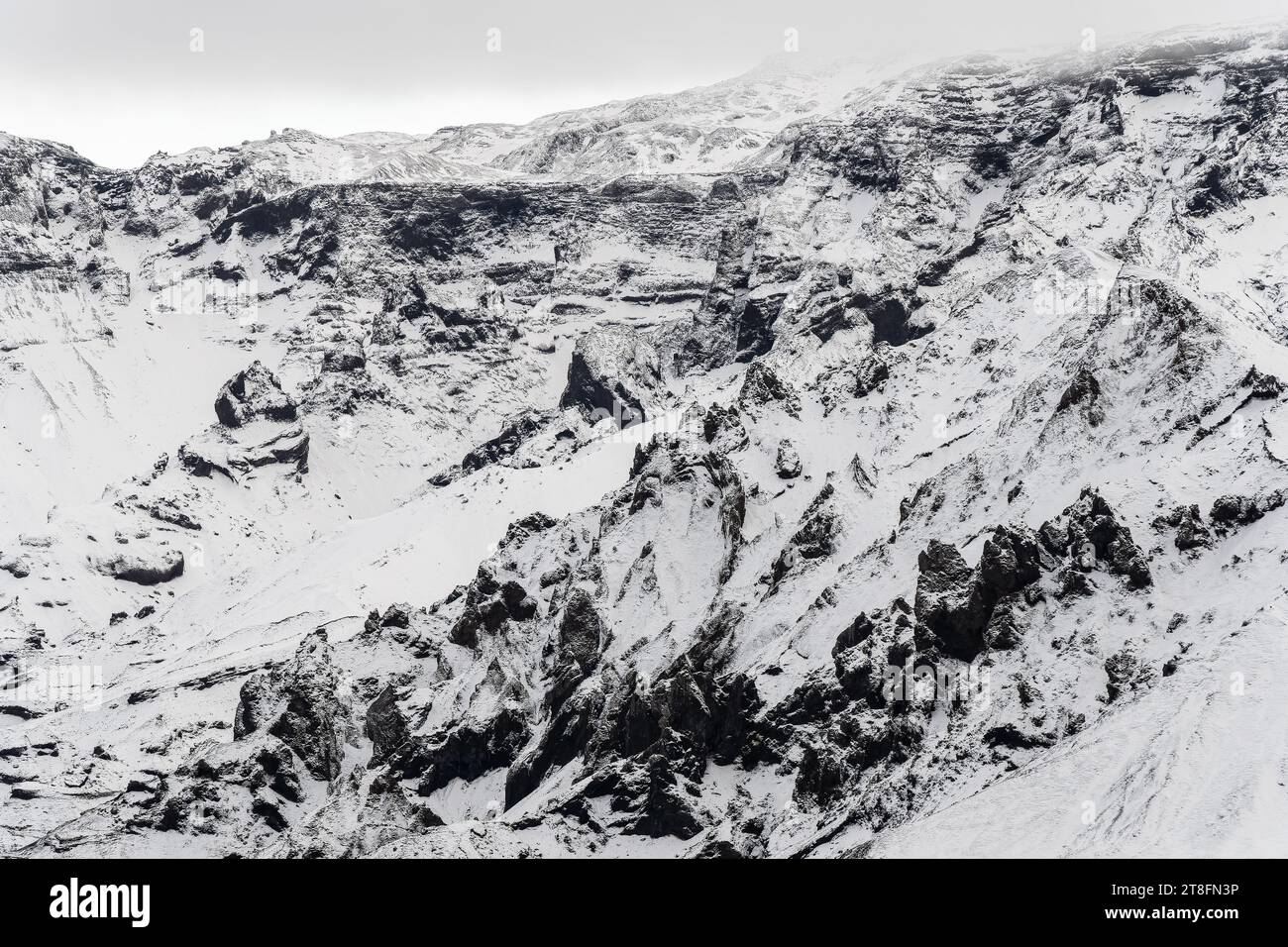Aerial view of snowy rocky terrain against foggy sky, showcasing the ...