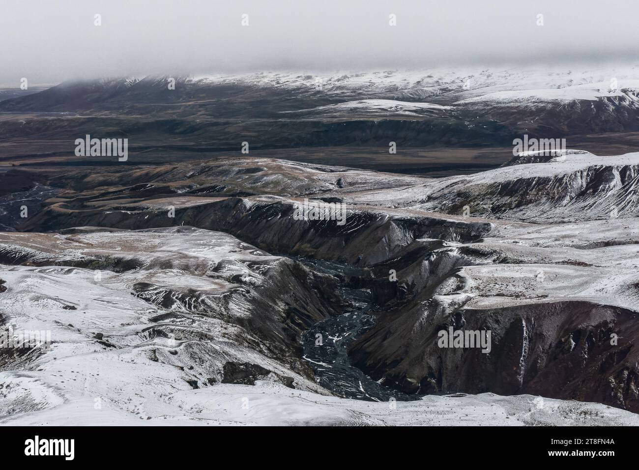 Aerial view of river between snow-draped canyon cutting through the ...