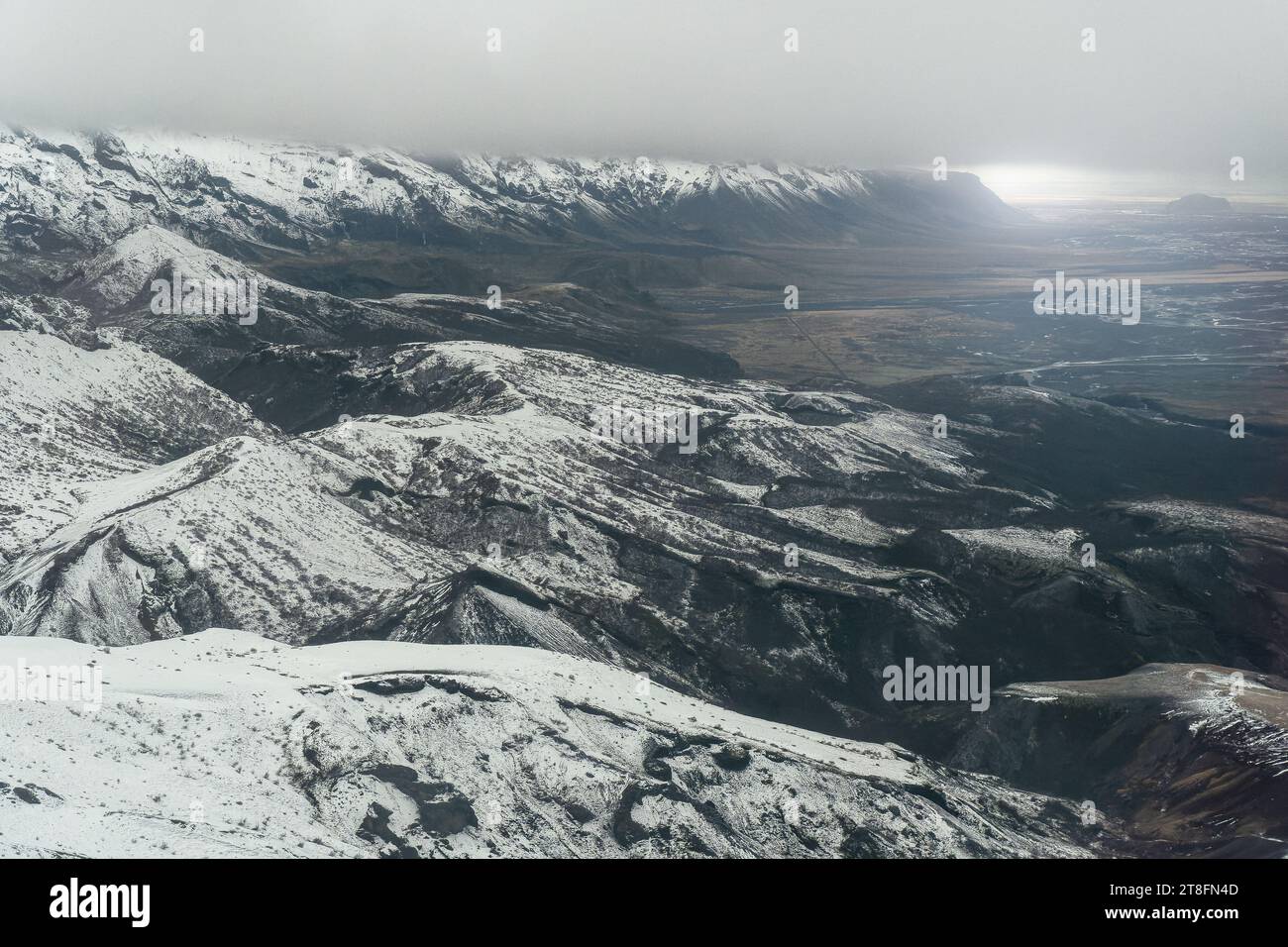 Aerial view of a snowy mountainside foreground giving way to a vast ...