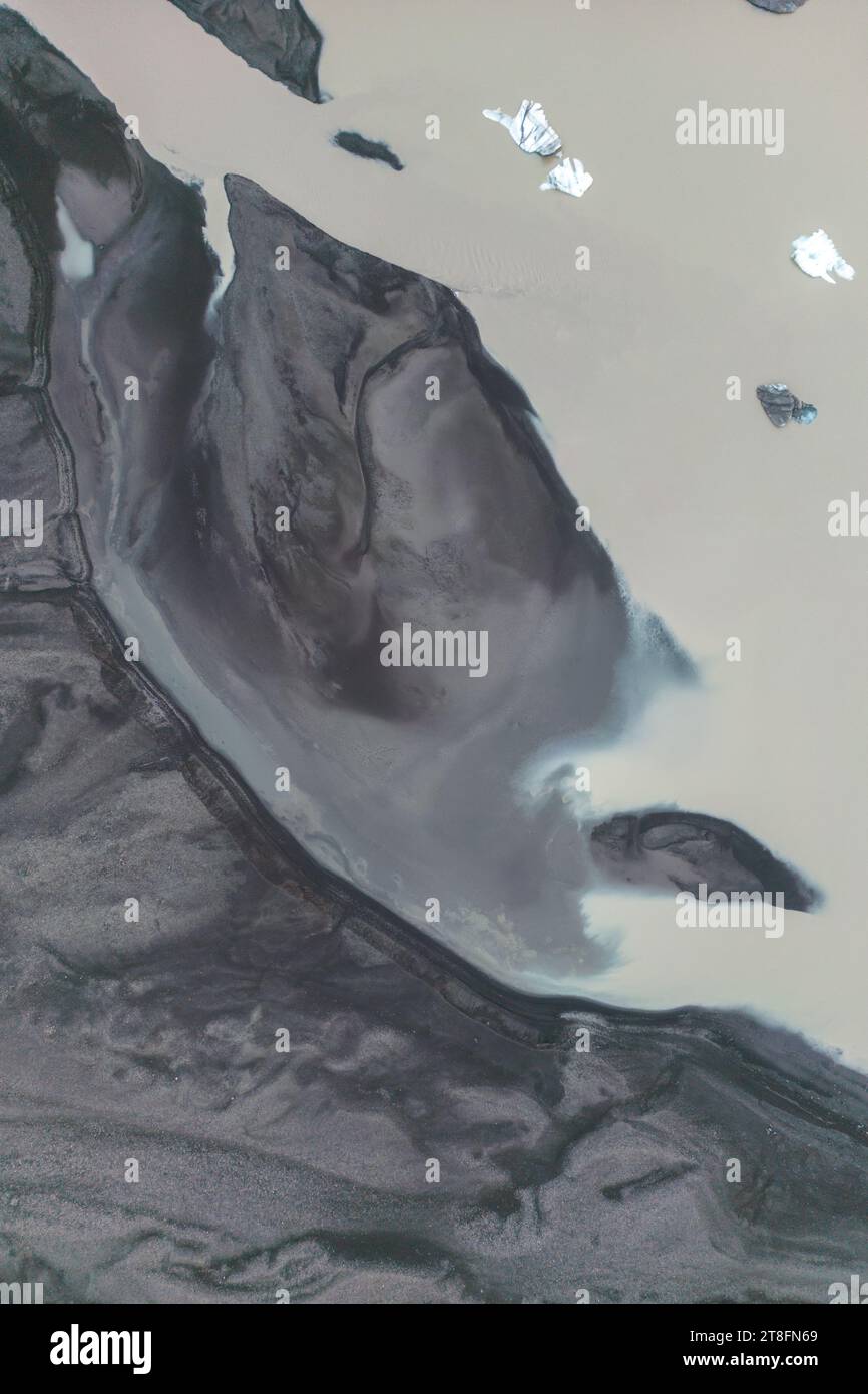 An aerial shot of glacial rivers flowing through the volcanic ash and ...