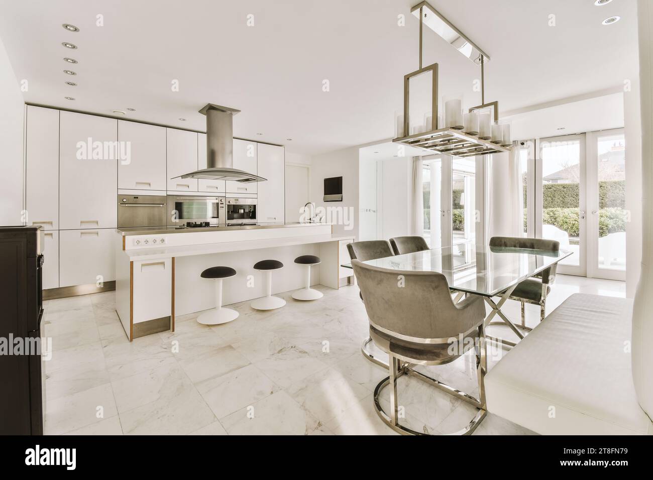 Dining table and chairs placed in front of open plan modern kitchen ...