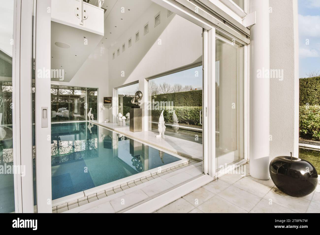 Calm swimming pool inside luxurious modern house with white walls and ...