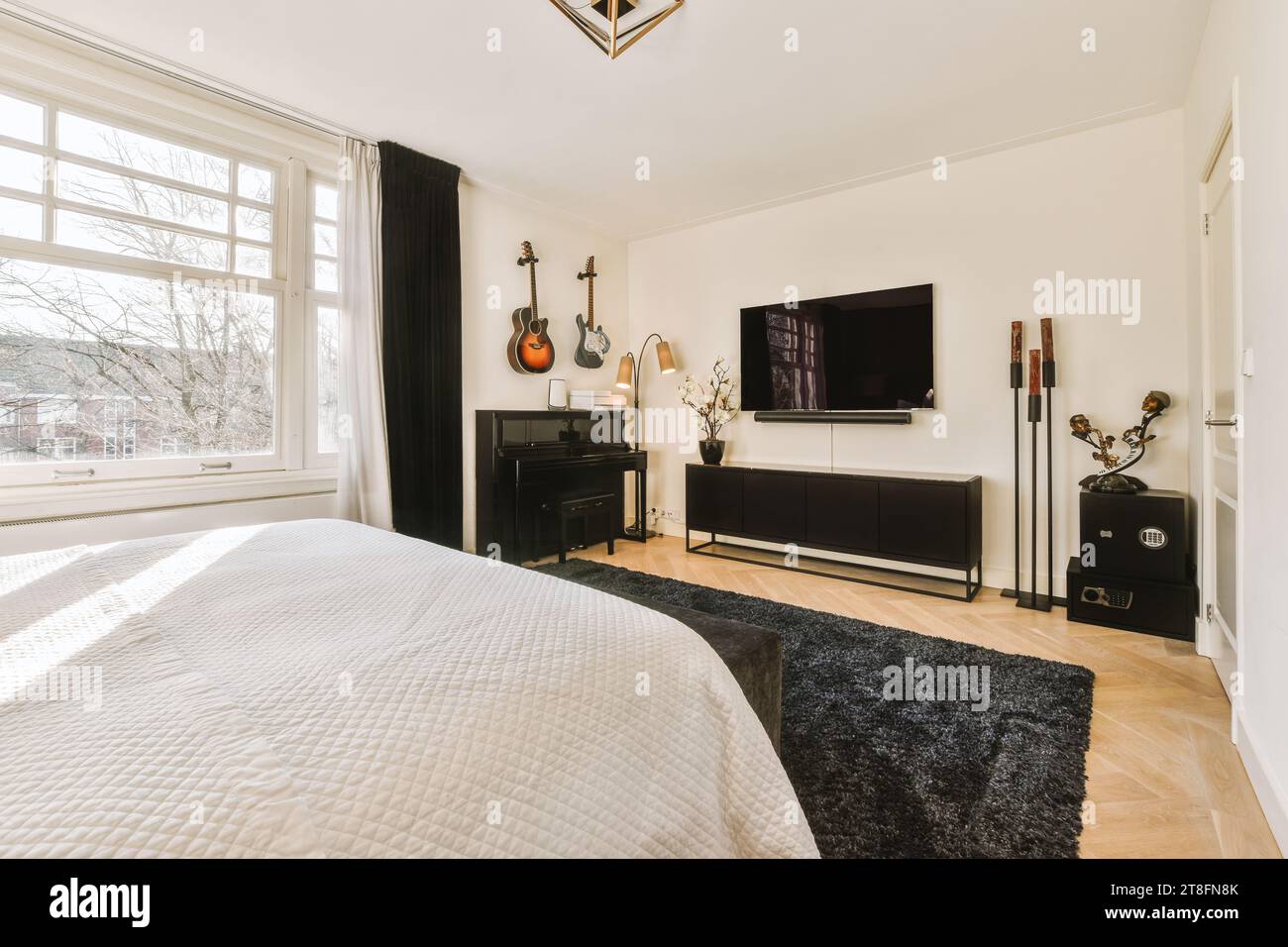 Comfortable bed with television and musical instruments in spacious ...