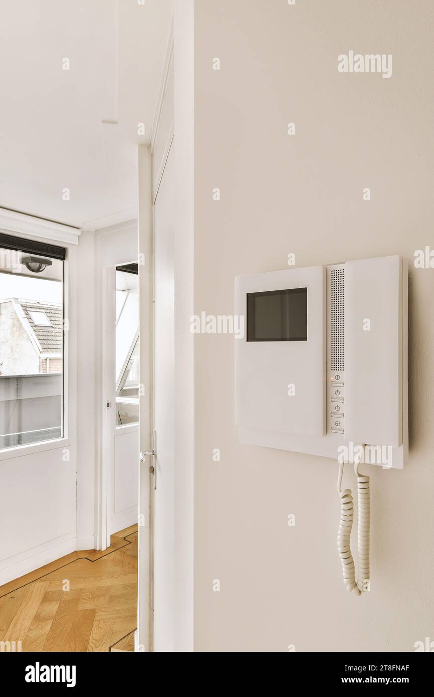 Intercom mounted on white wall by empty hallway in light contemporary ...
