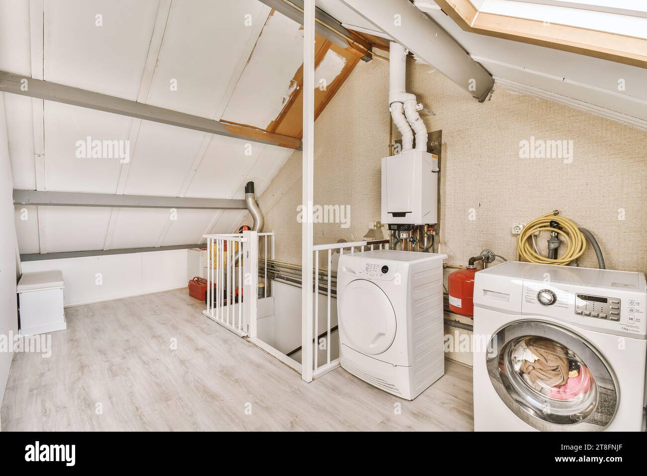 Washing and dryer machines in attic laundry room with white walls at ...