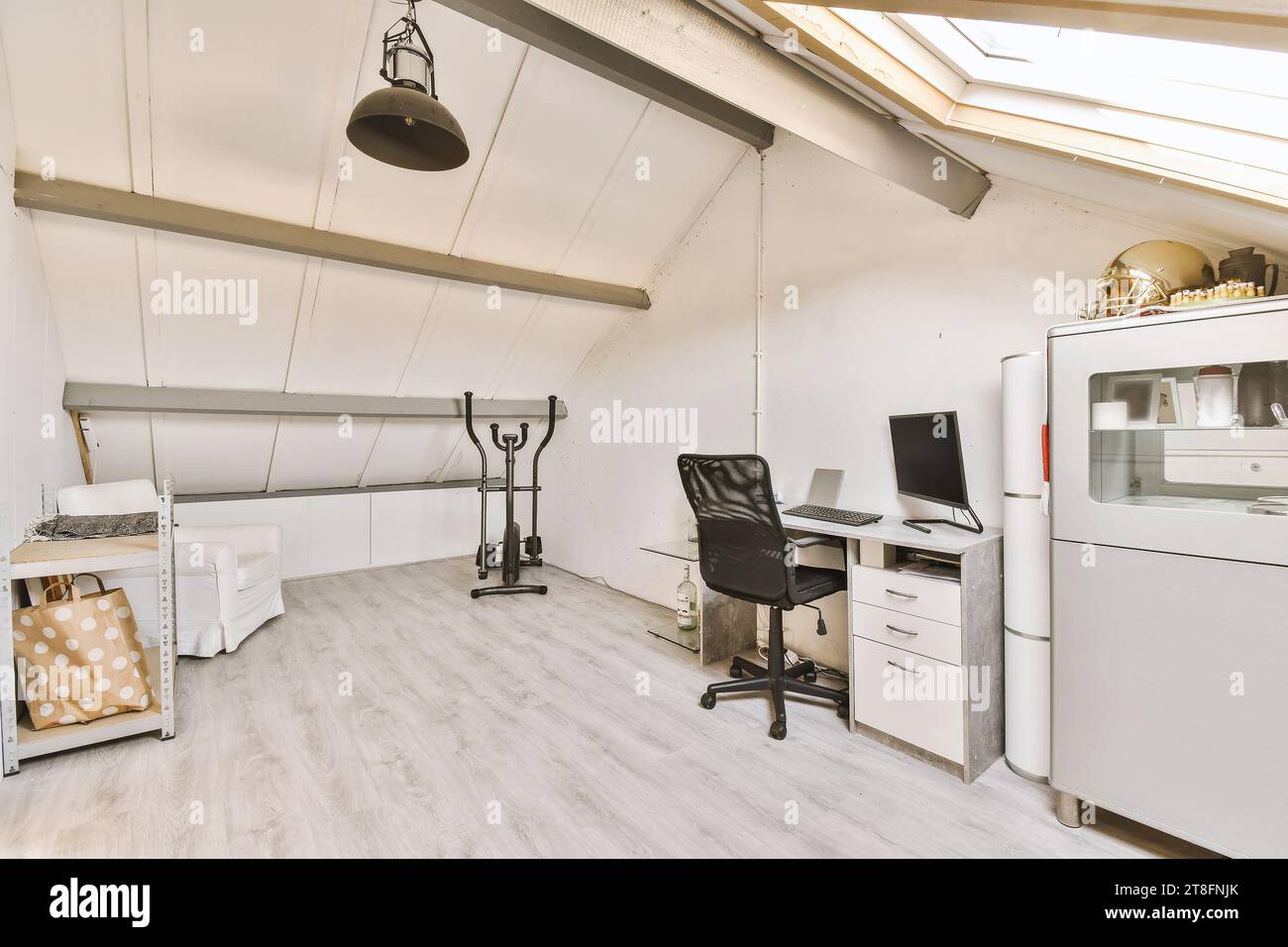 Desktop computer with laptop on desk and empty chair with cabinet in ...