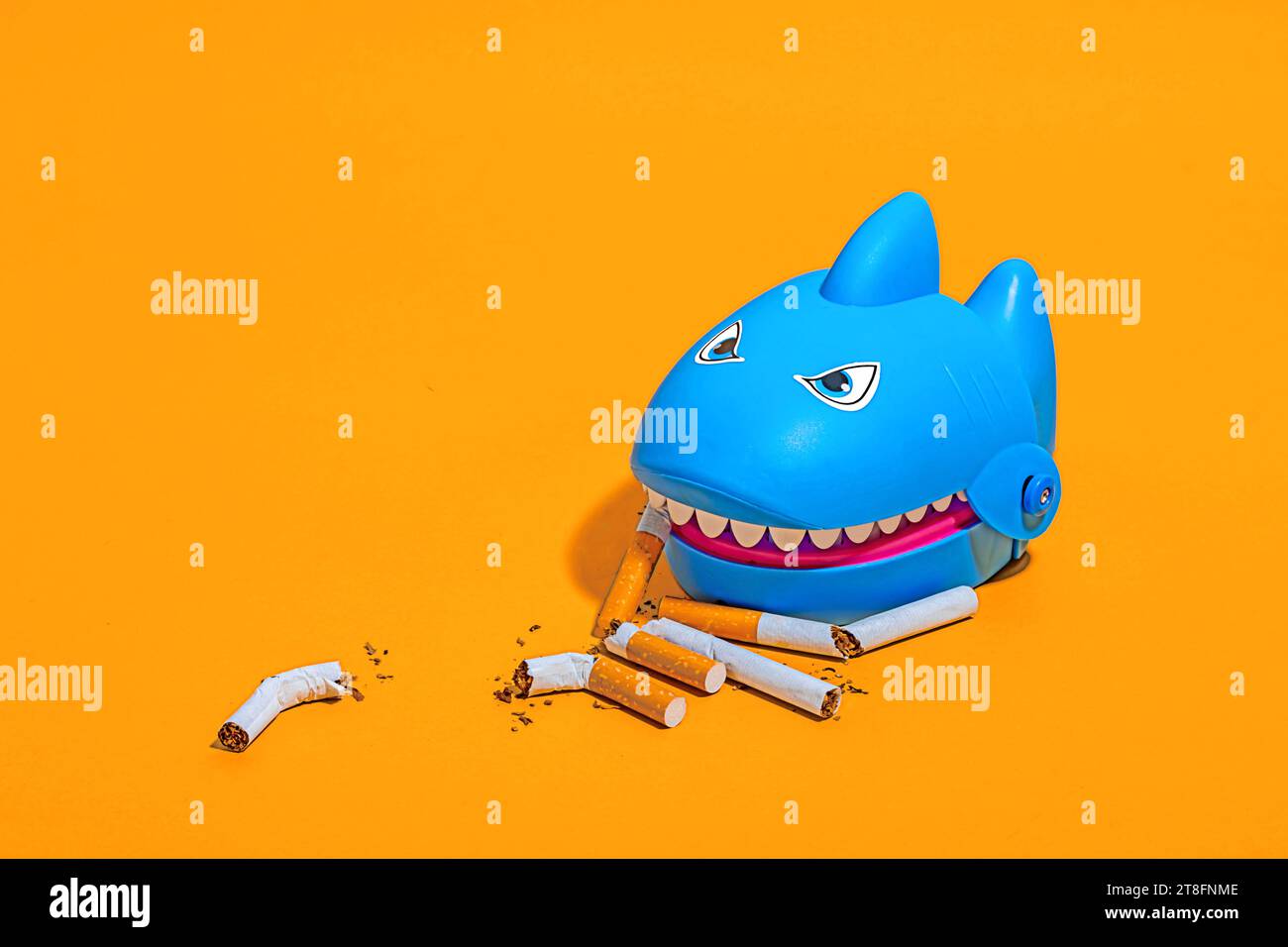 High angle of blue shark toy amidst scattered cigarette butts on a ...