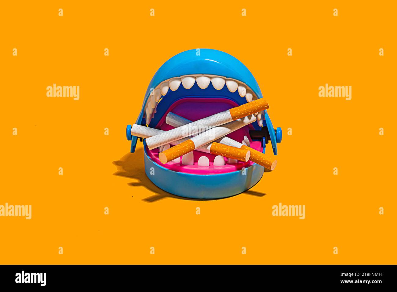 Vibrant blue plastic toy shark with opened mouth with cigarette butts ...