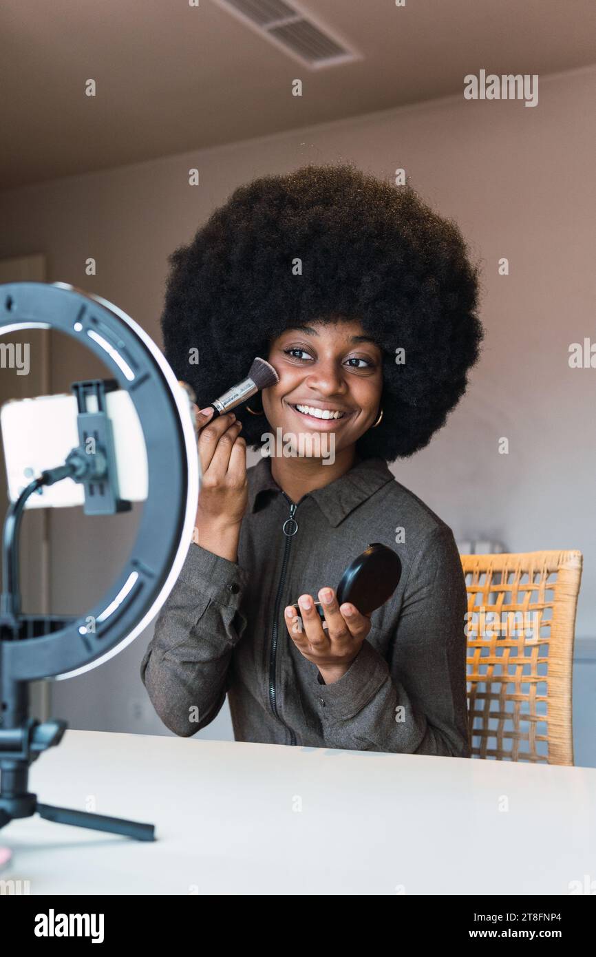 Content African American female blogger with Afro hairstyle applying ...